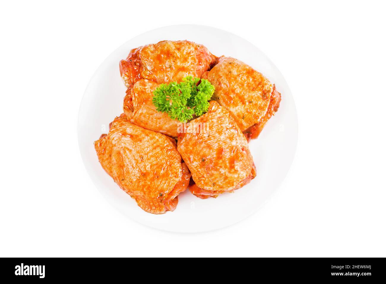 Raw marinated in red sauce chicken thighs on a white plate, on a white ...