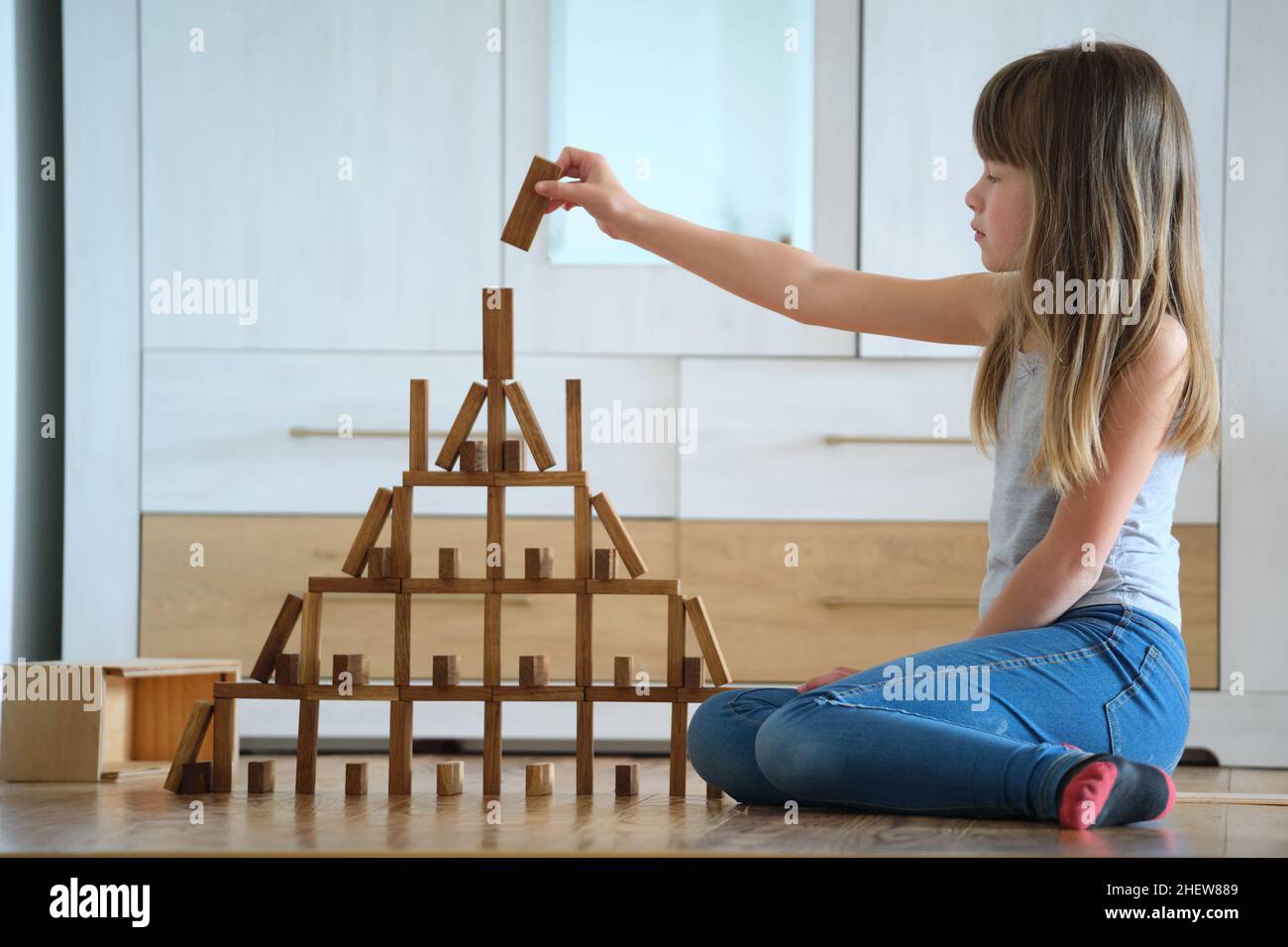 Creative child girl playing with game stacking wooden toy blocks in ...