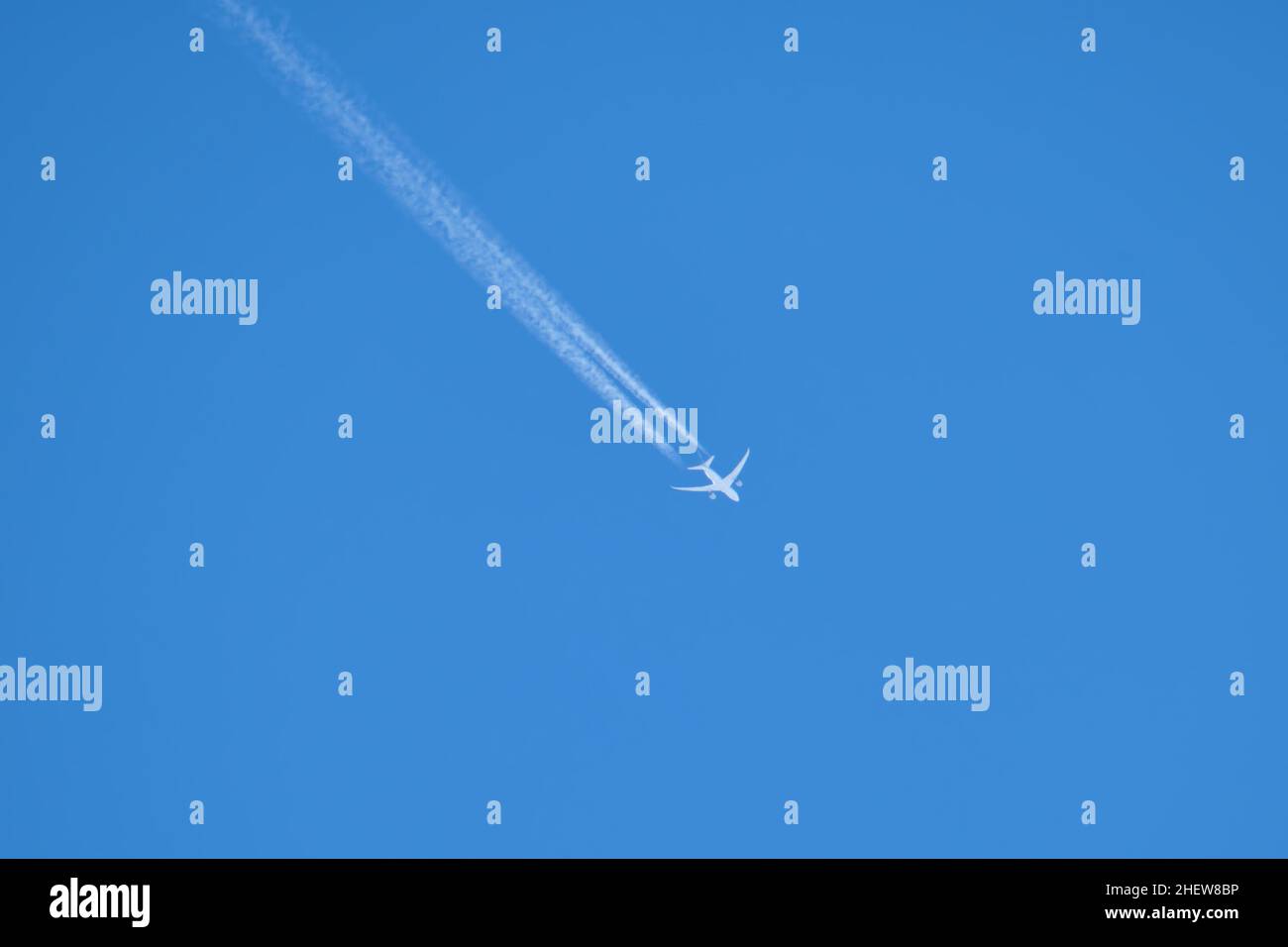 Distant passenger jet plane flying on high altitude on clear blue sky ...