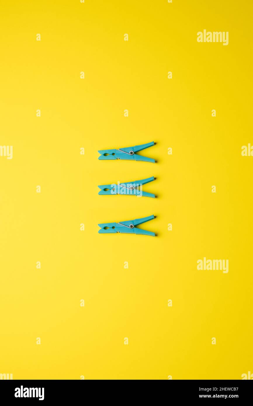 three blue clothespins centered and aligned vertically on a yellow ...