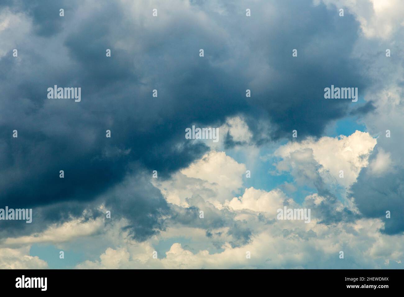 heavy dark rain clouds with storm and blue sky with puffy clouds in ...