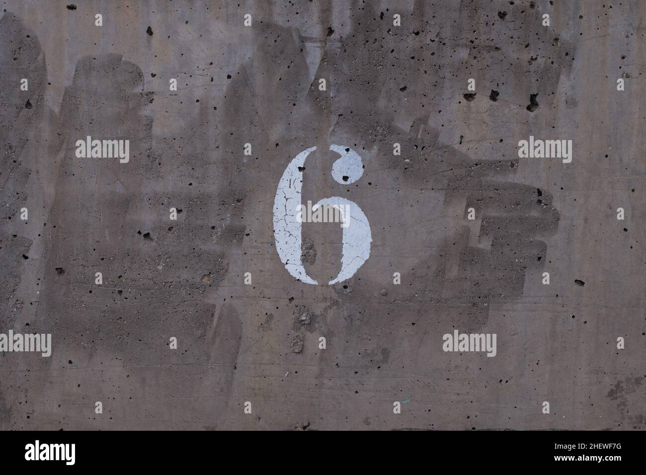 number 6 on a concrete wall with darker stains Stock Photo - Alamy