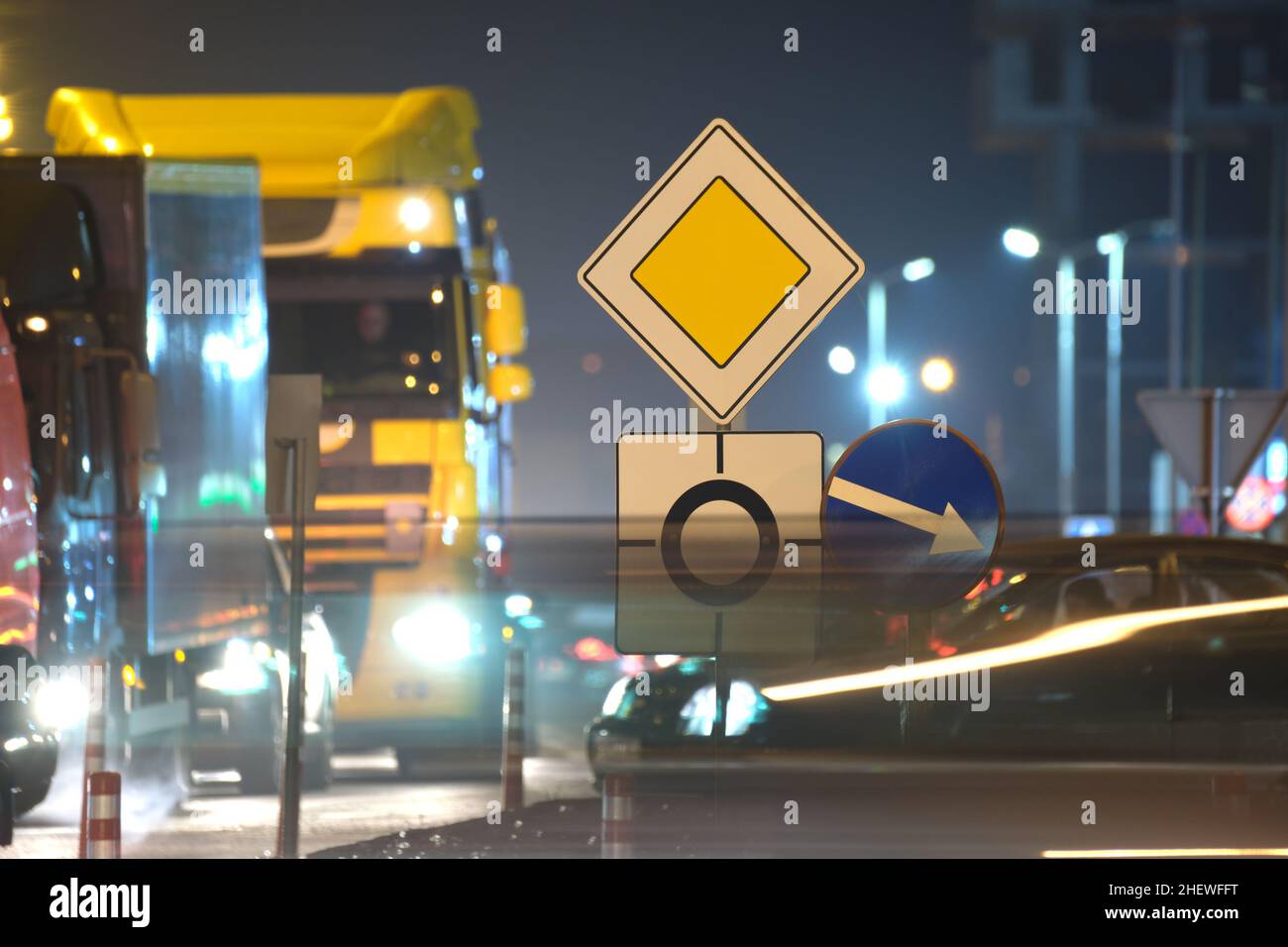 Roundabout road signs with blurred cars on city street traffic at night ...