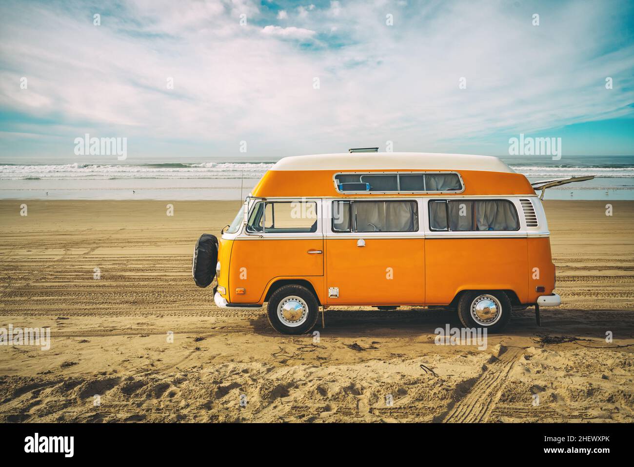 Vintage yellow van on the beach with cloudy sky on background, retro ...