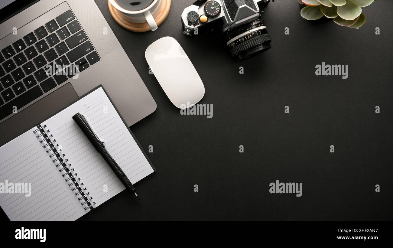 Modern hipster dark workspace with laptop computer, diary, camera ...