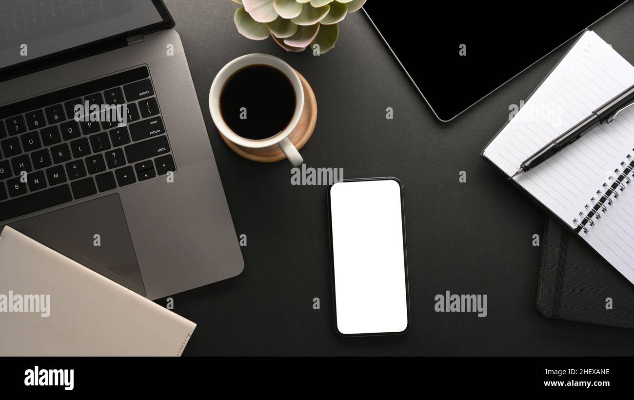 Modern dark workspace with laptop computer, coffee cup, stationery and ...