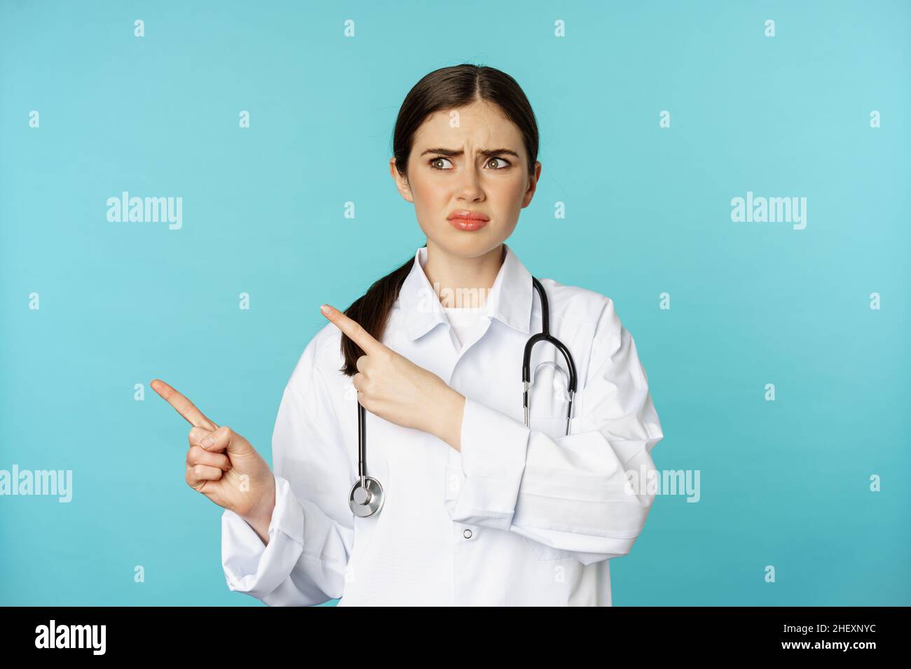 Confused, disappointed medical worker, frowning while pointing fingers ...