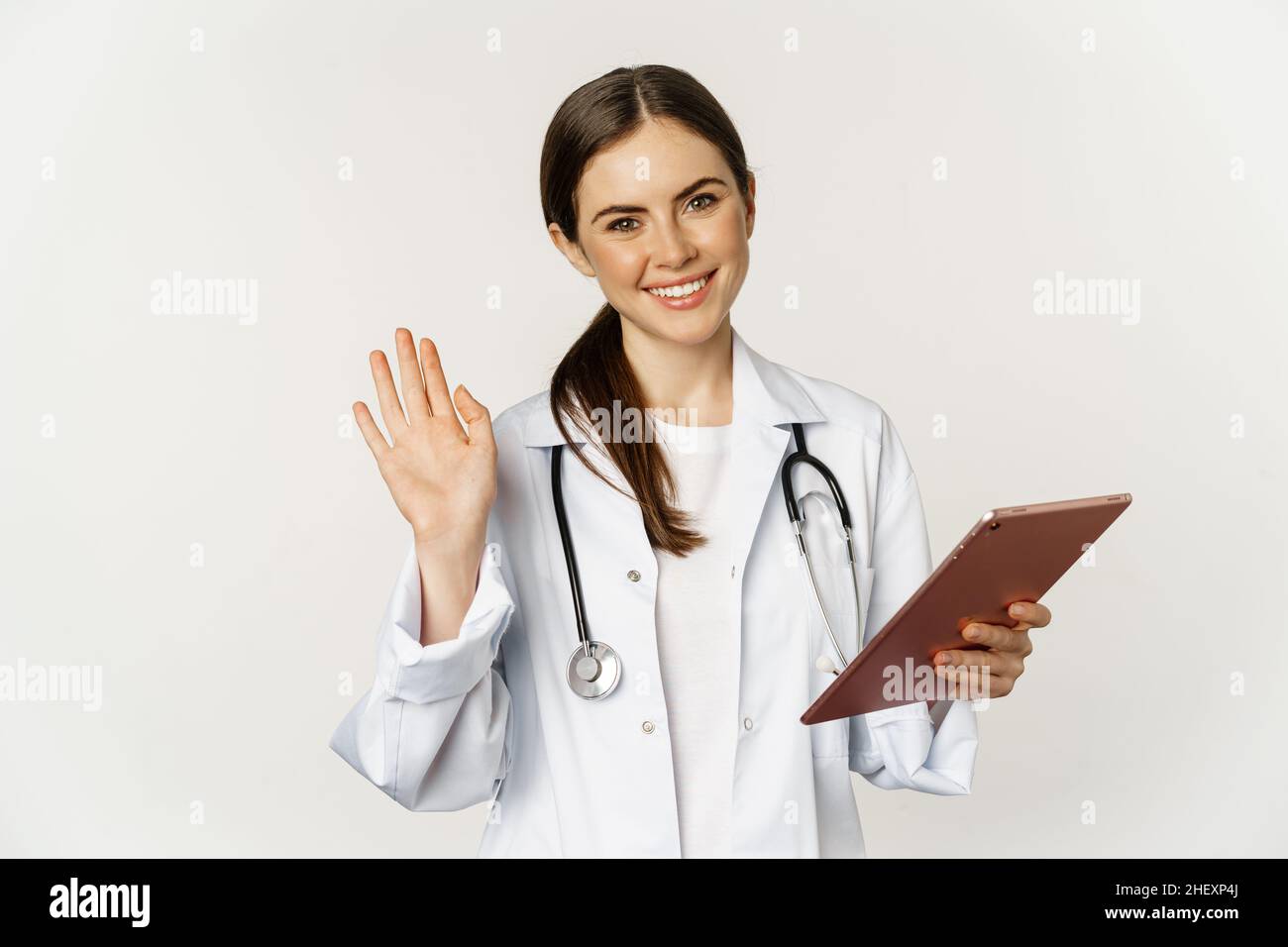 Friendly woman doctor, physician waving hand say hello, holding digital ...