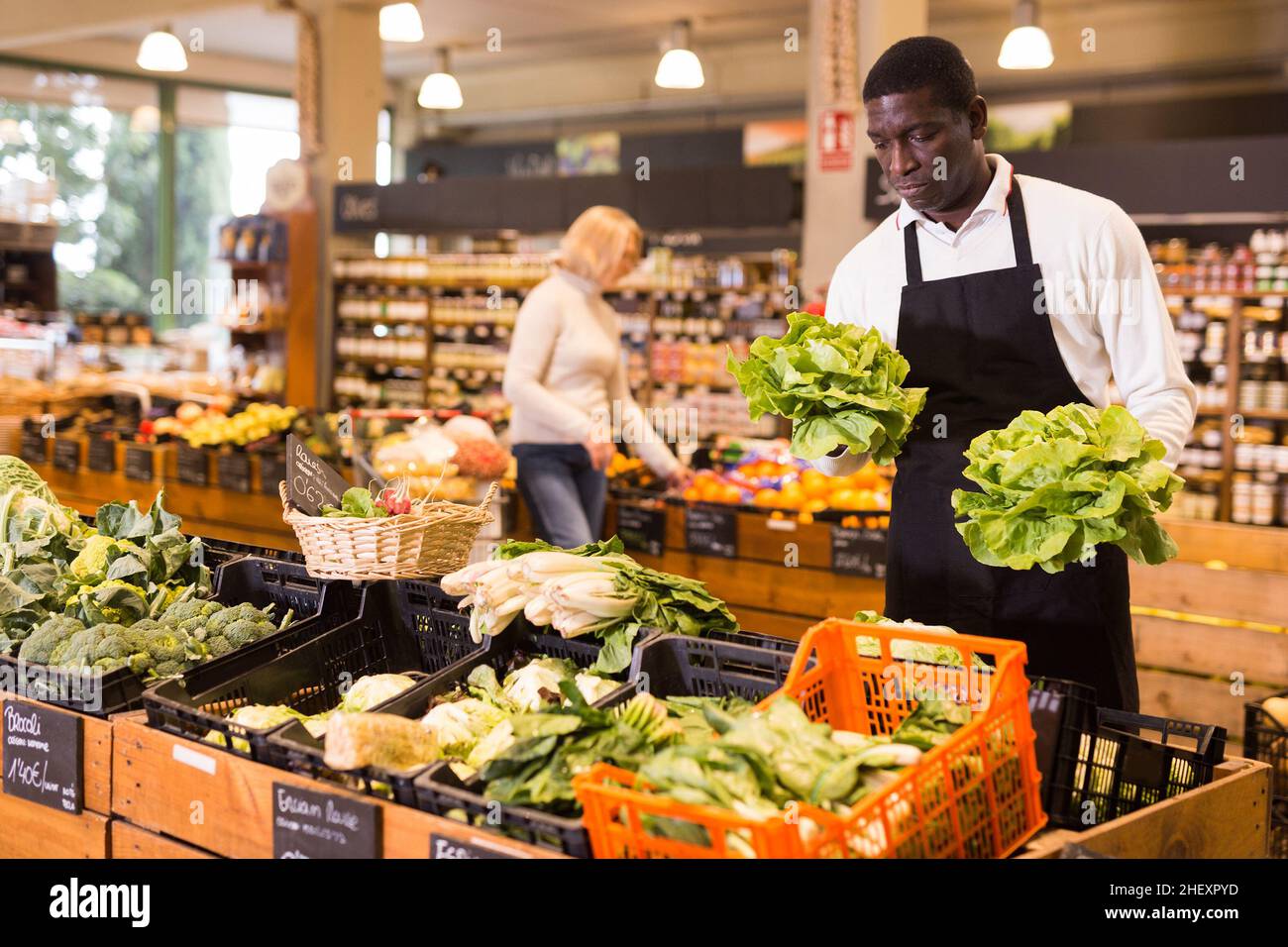 Salesman putting vegetables on store showcase Stock Photo - Alamy