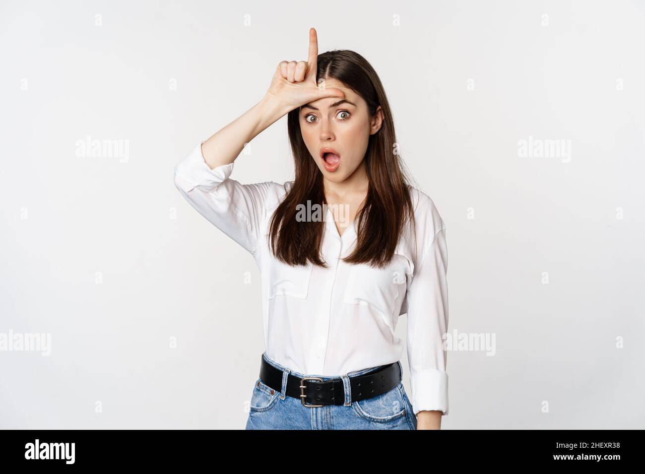 Young woman mocking loser, showing L word sign on forehead and gasping ...