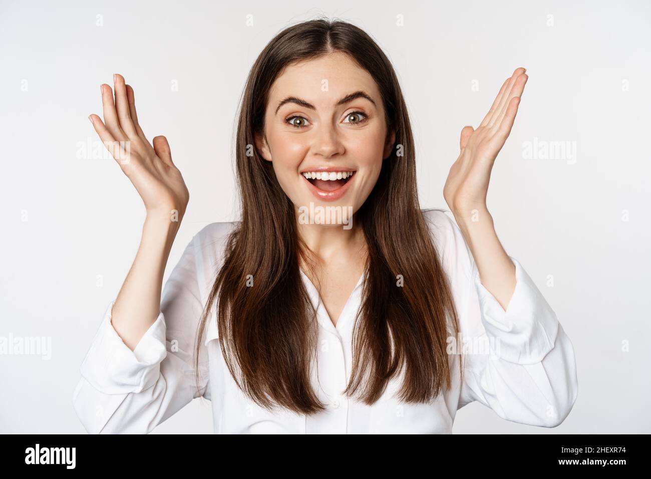 Enthusiastic young woman celebrating, smiling and raising hands up in ...