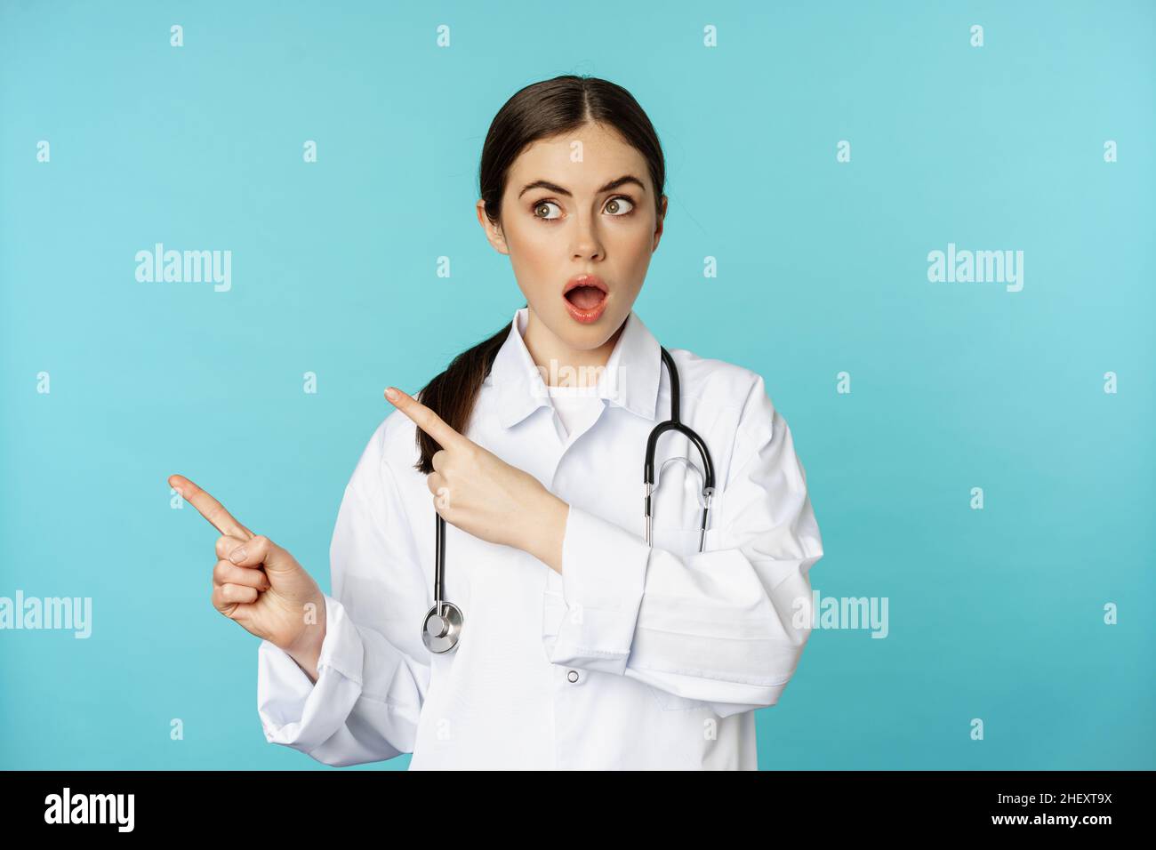 Surprised female doctor, physician with stethoscope, pointing and ...
