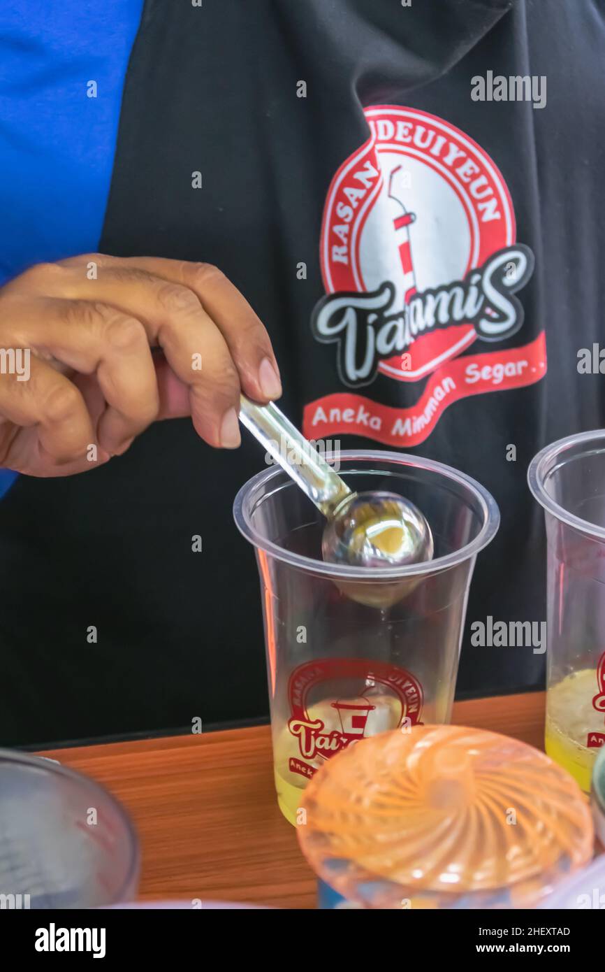 pouring a basil with stainless steel spoon into a transparent plastic ...