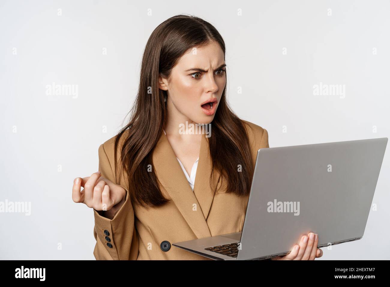 Shocked and disappointed business woman looking at laptop screen with ...