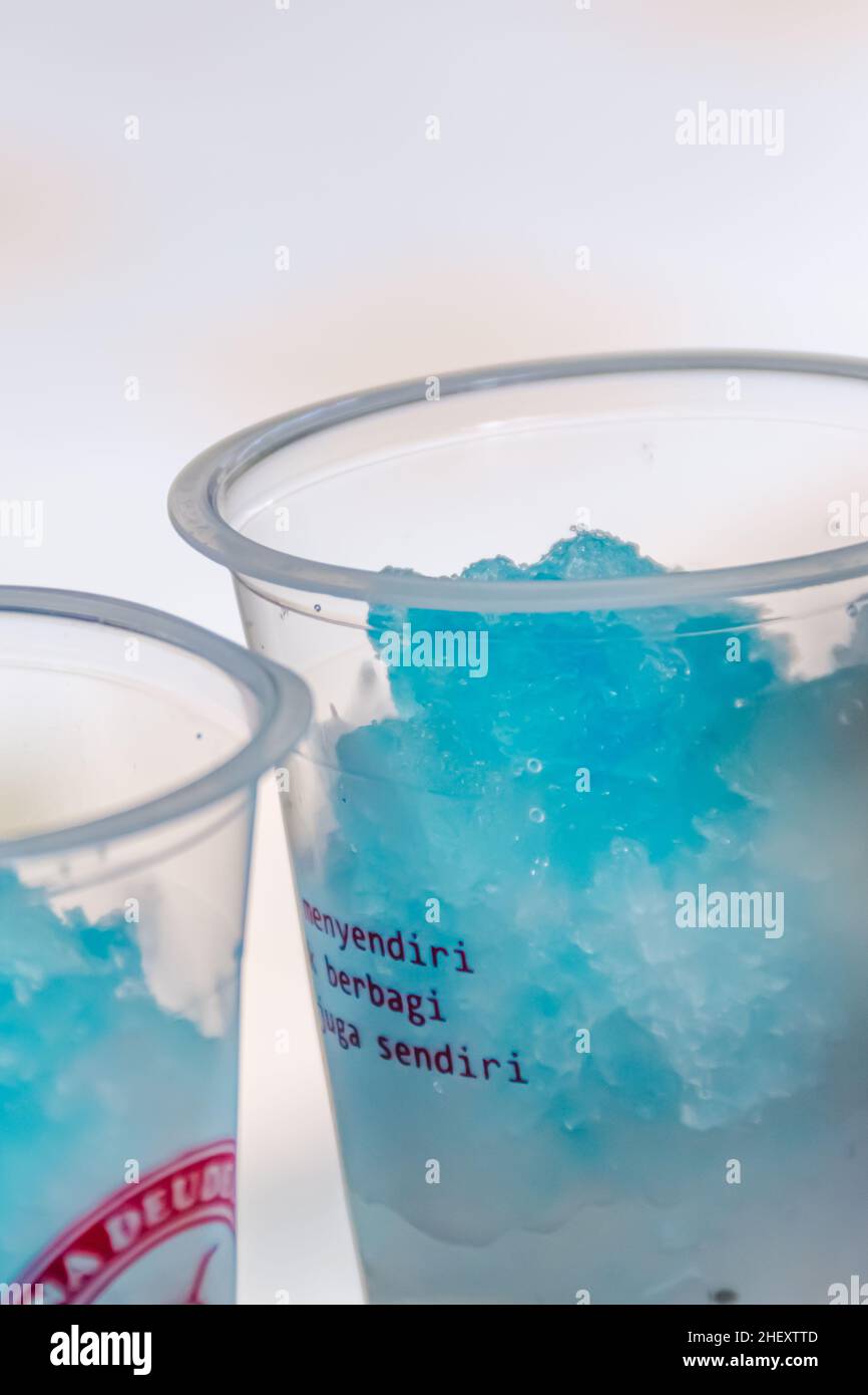 cold shaved ice with poured blue syrup for a fresh blue mojito drink in ...