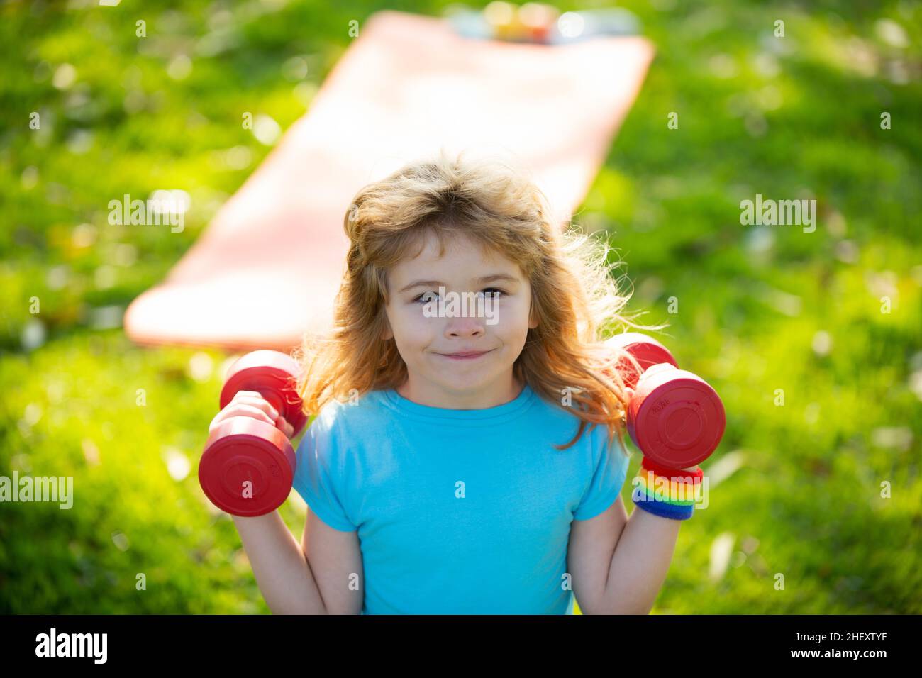 Fitness child boy raising a dumbbell. Cute child training with ...