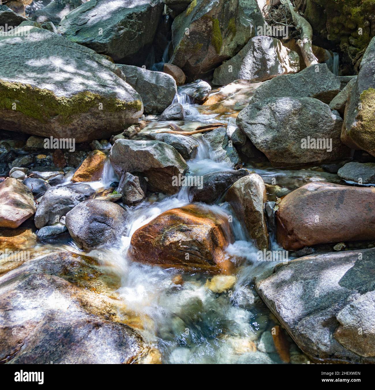 colorful stones in the clear cold water of a creek with water from ...