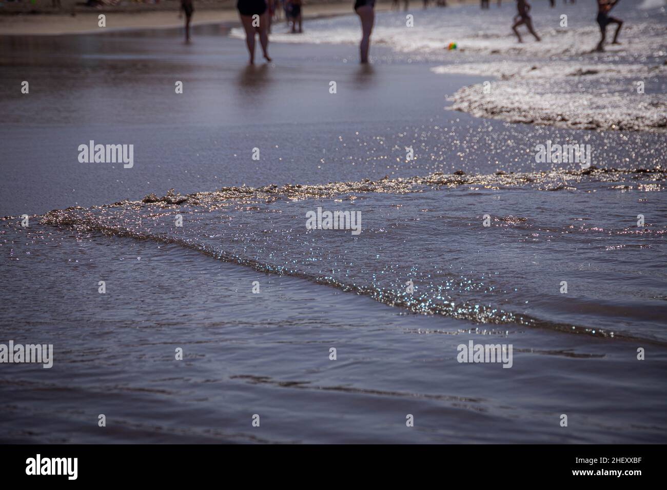 Smooth beach where people walk and small waves roll Stock Photo - Alamy