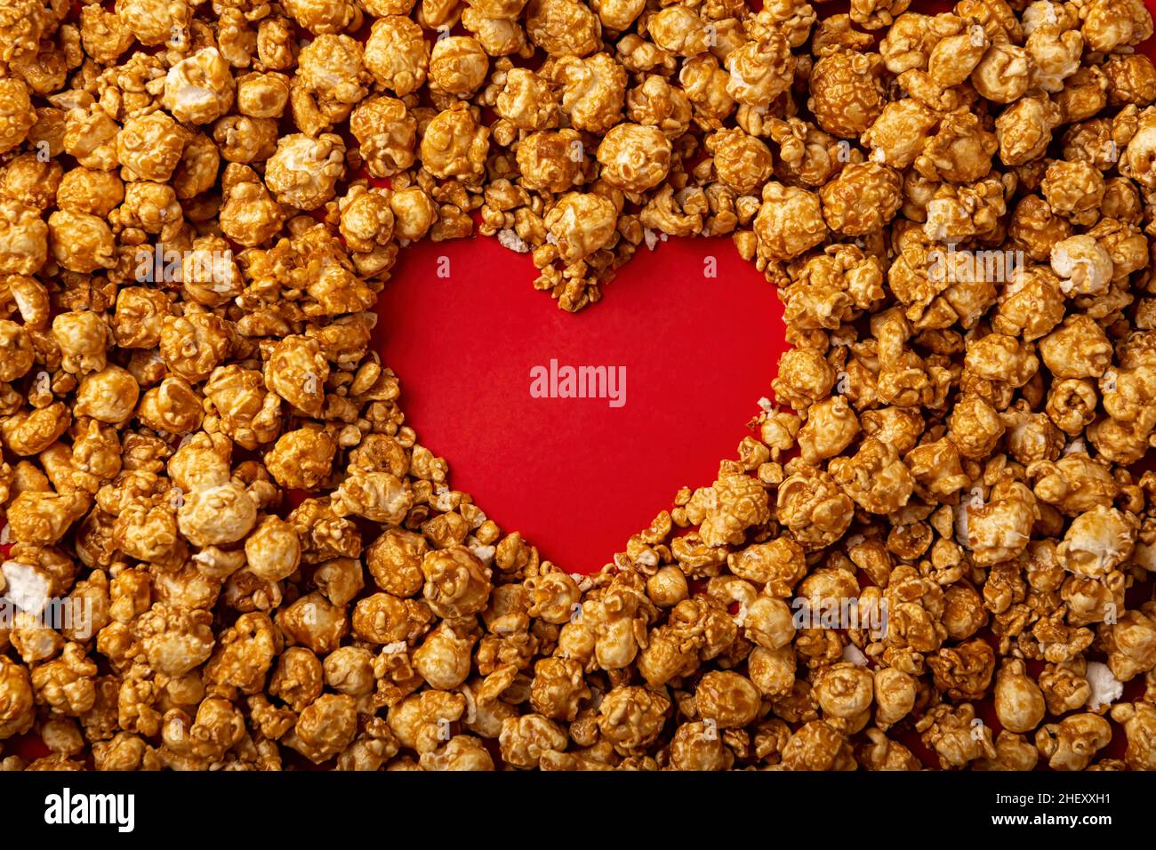 love concept image of heart shape frame made of caramel popcorn on red ...