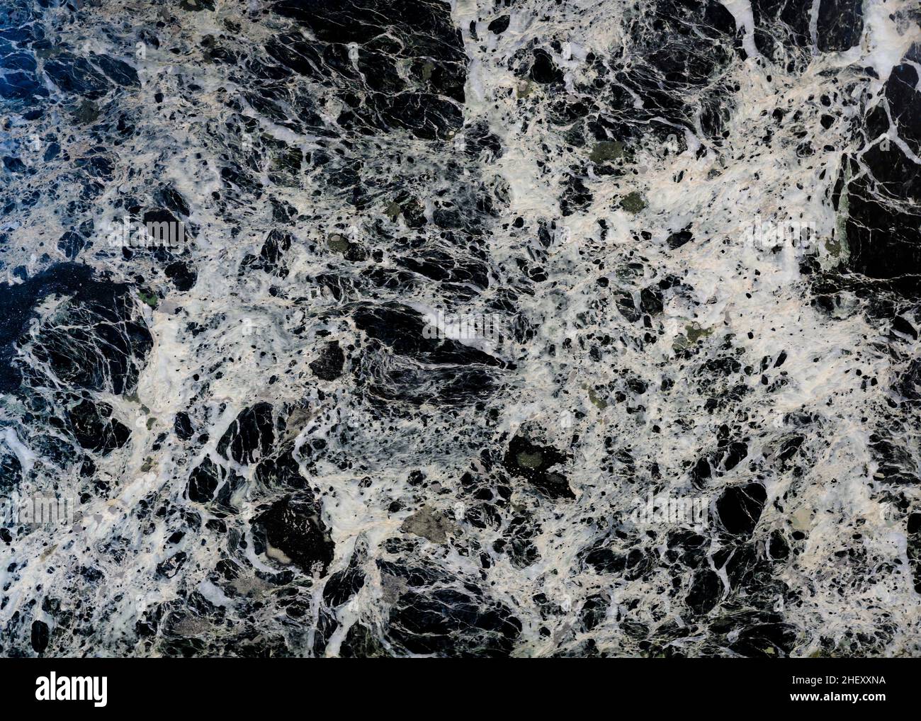 Polished granite surface with abstract beige streaks on a dark ...