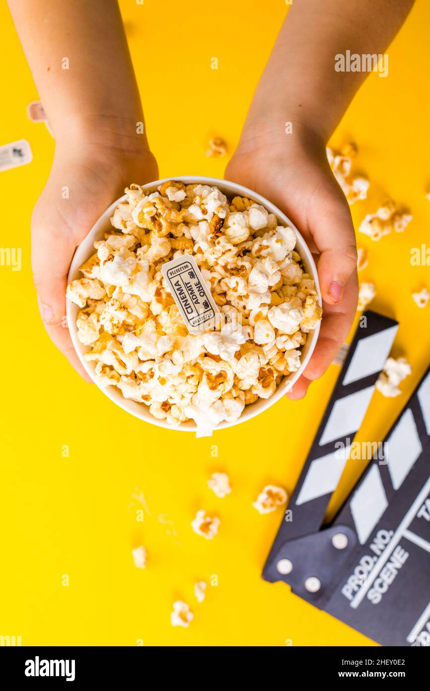 Popcorn viewed from above on yellow background. Child eating pop-corns ...