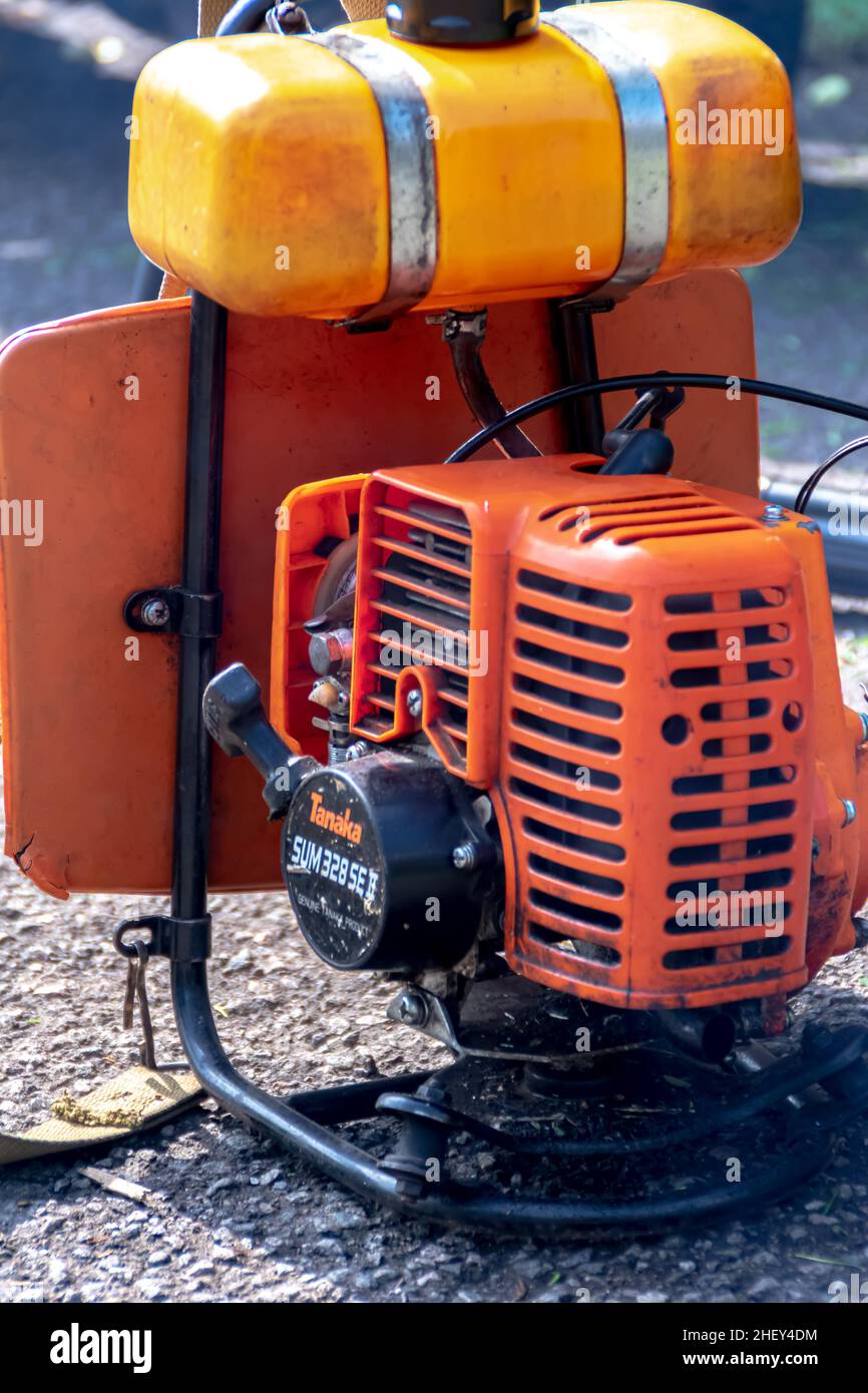 Close-up view of the two strokes engine of the orange grass cutting or ...