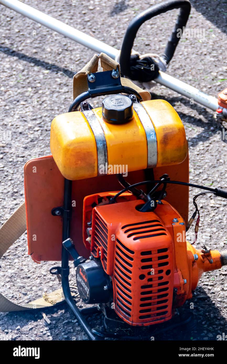Close-up view of the two strokes engine of the orange grass cutting or ...