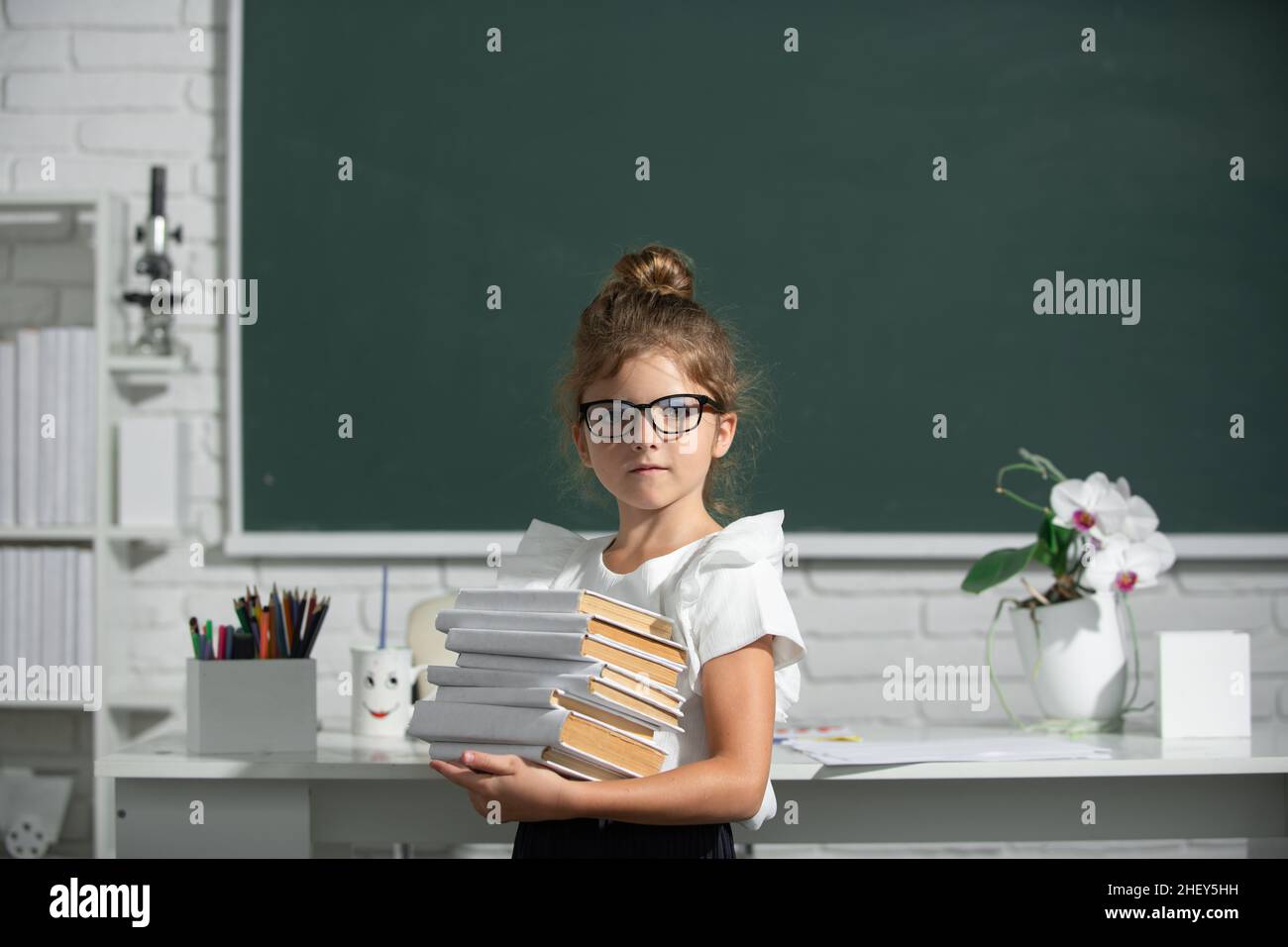 Nerd school girl in glasses with books on blackboard. School child in ...