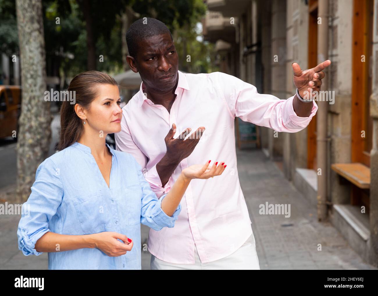 Man pointing way to young female Stock Photo - Alamy