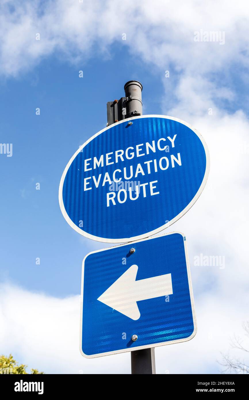 sign emergency evacuation route in blue under blue sky Stock Photo - Alamy