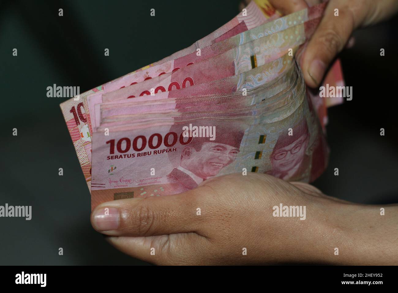 Woman hand showing rupiah Indonesian money isolated on dark background ...