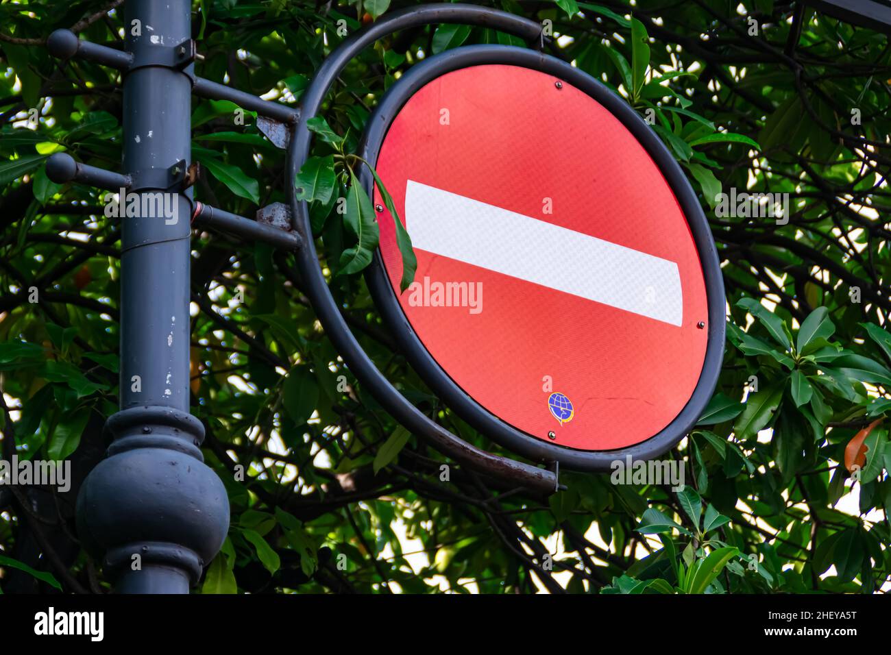 Red stop or forbidden street sign hanging on city lamp under the green ...