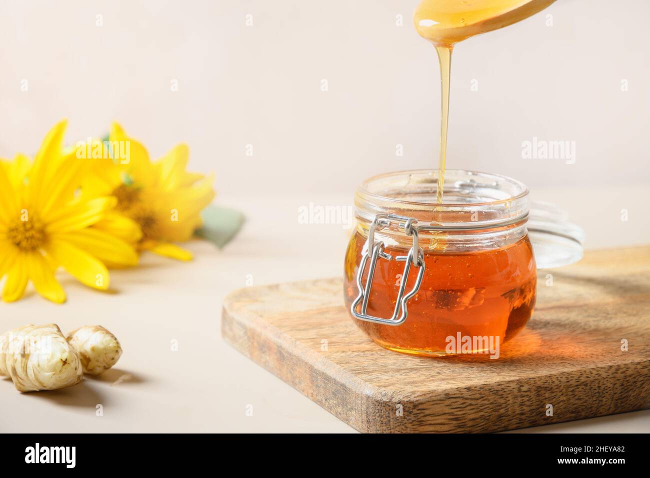 Pouring Jerusalem artichoke syrup in glass jar on biege background ...