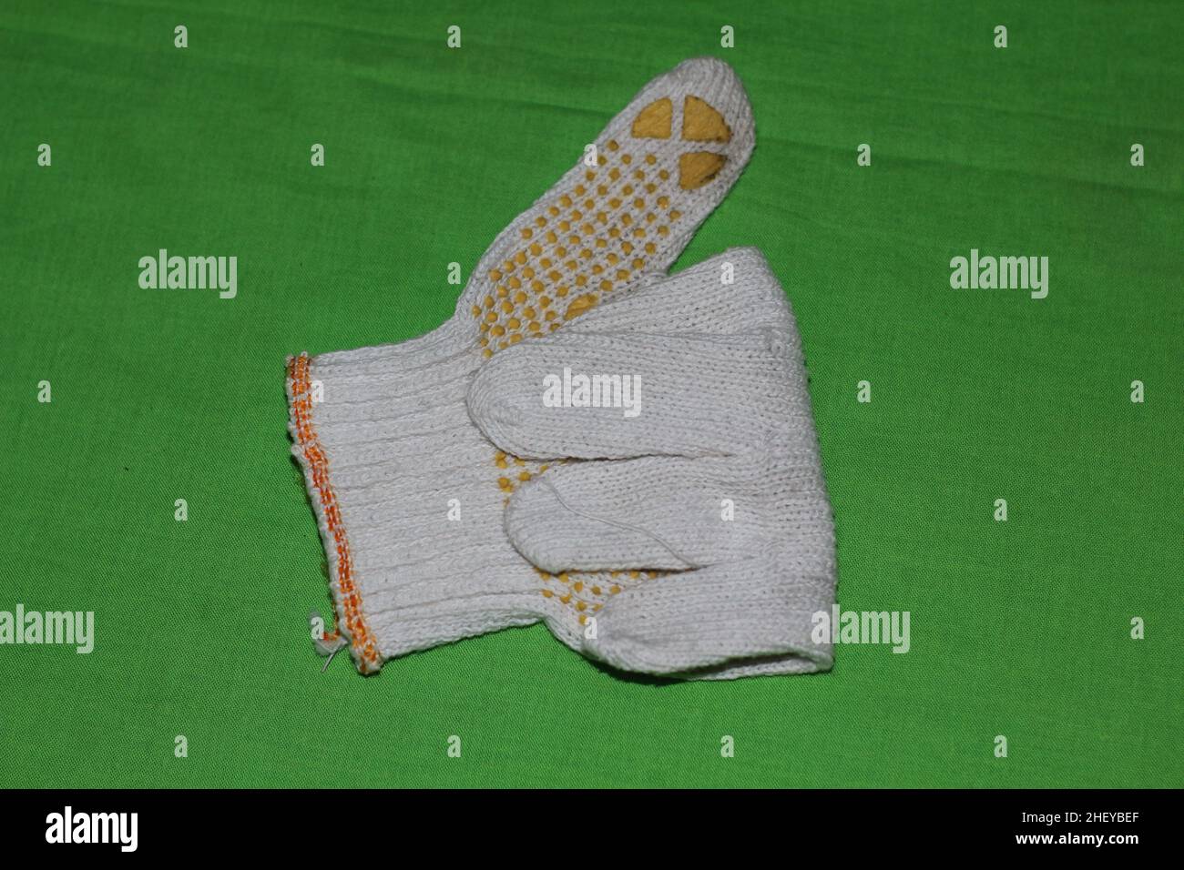 Folded gloves showing thumbs up isolated over green Stock Photo - Alamy