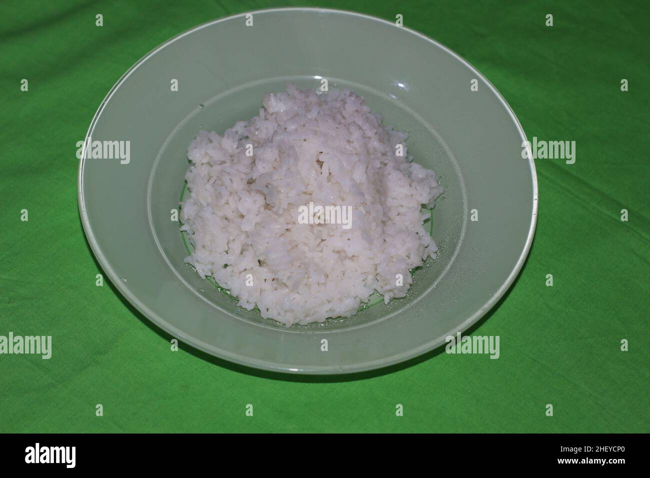 Cooked rice served on a plate to eat with green background Stock Photo ...