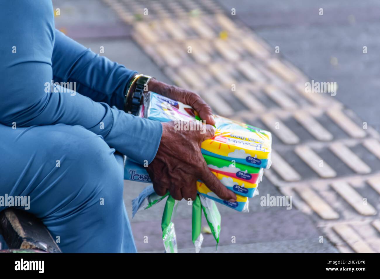 Old female street seller sit and wait for peddle the facial tissue for ...