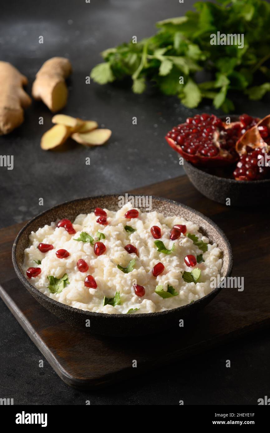 Curd Rice with pomegranate, cilantro, mustard seeds, ginger on a black ...
