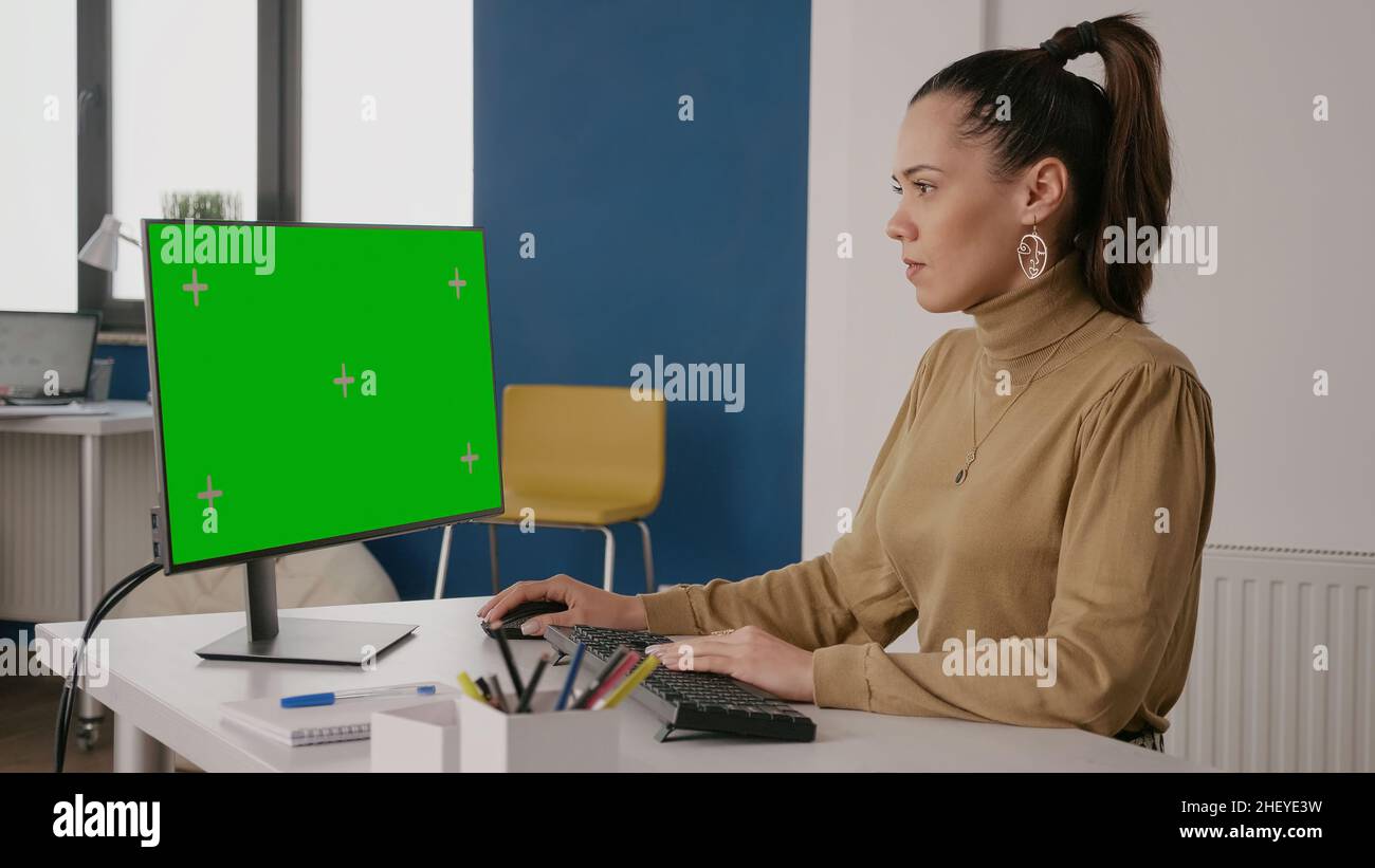Person looking at green screen on computer display in office, working ...