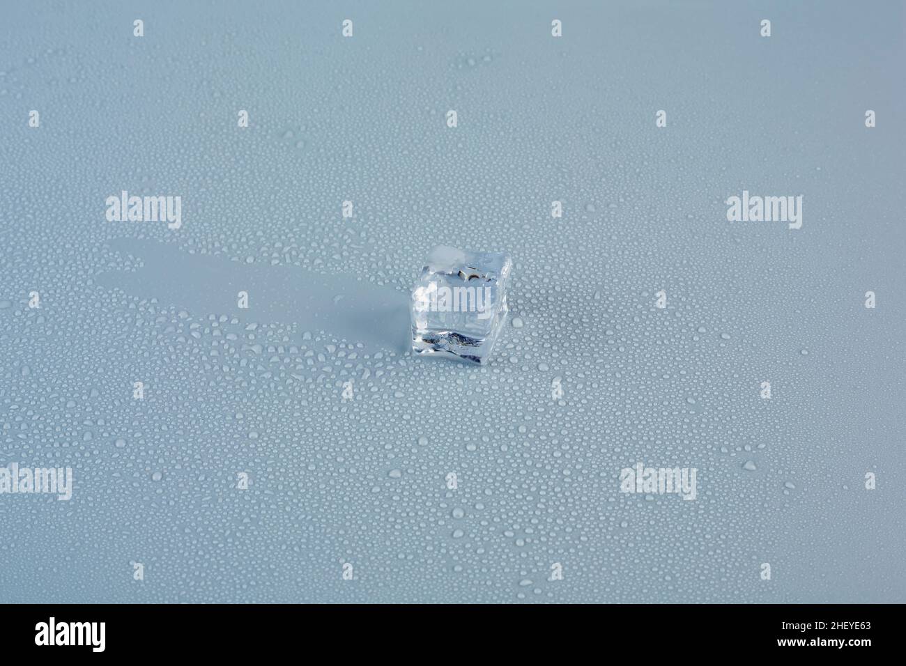 One ice cube on a gray background behind it is left a trail of sliding ...