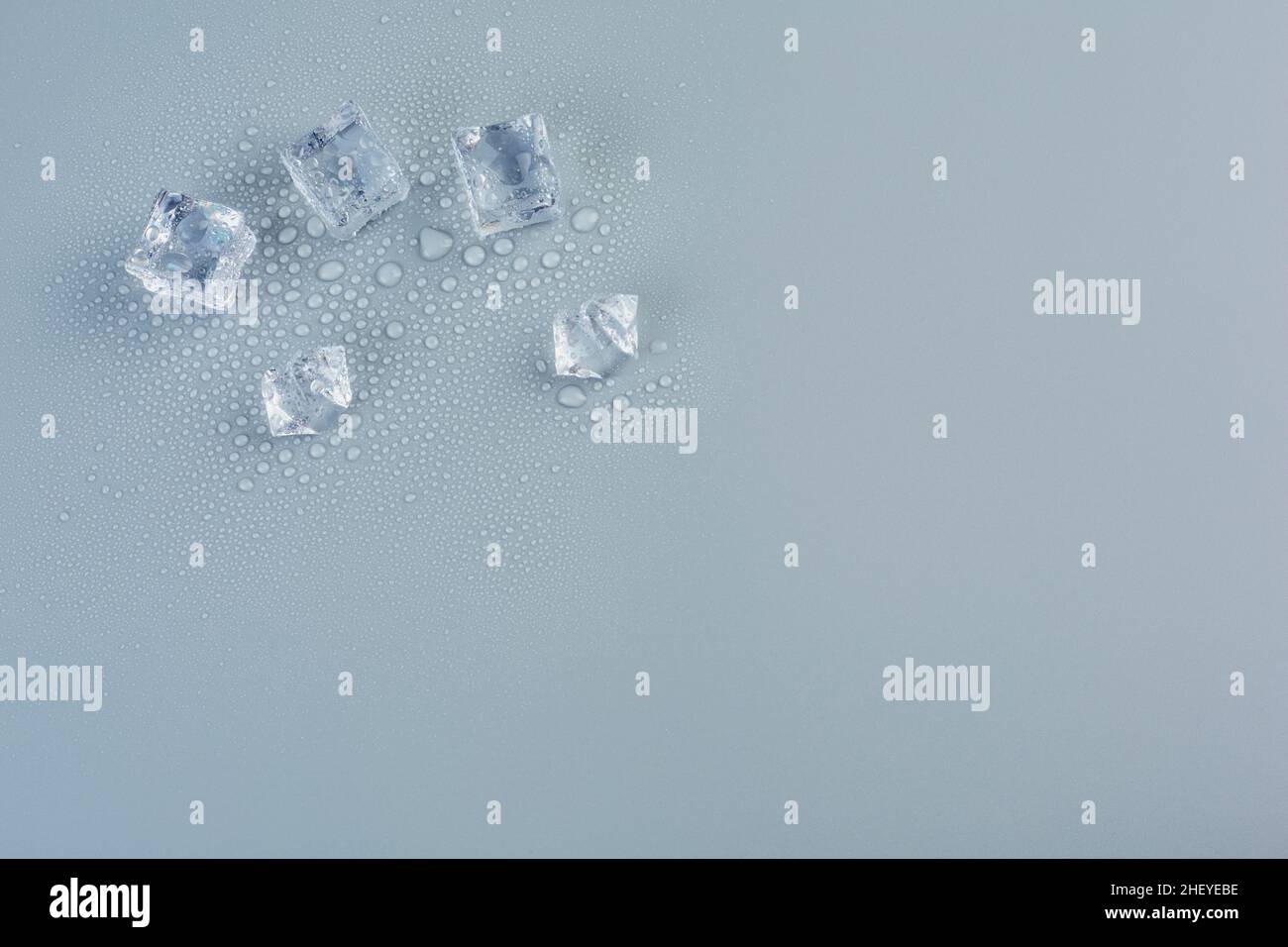 Five ice cubes in melted water on a gray background Stock Photo - Alamy