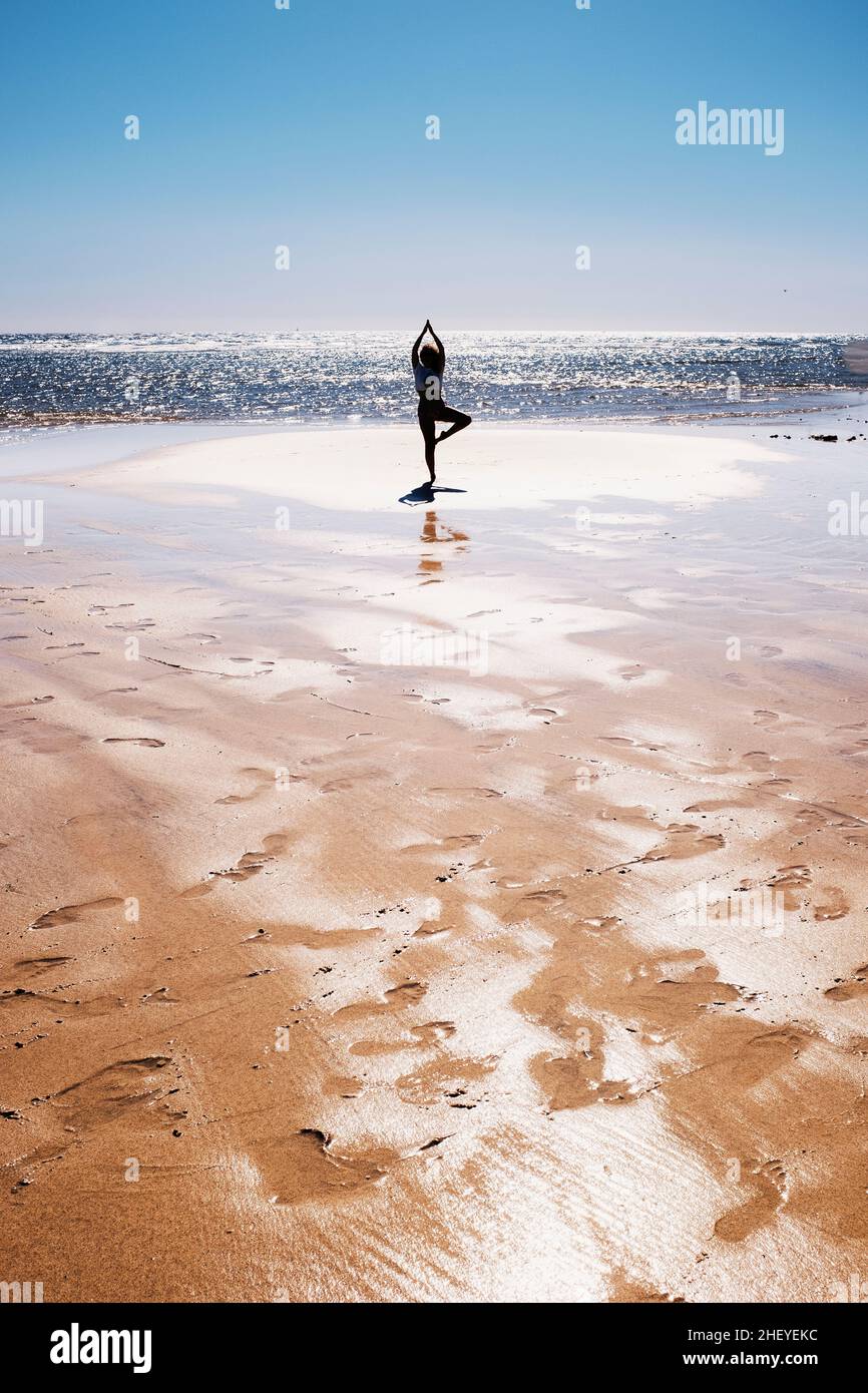 Yoga balanced posture for woman in silhouette standing at the beach ...