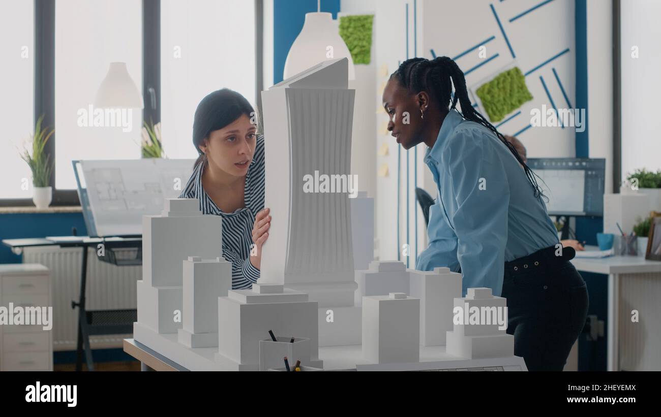 Team of diverse women working together with building model to design ...