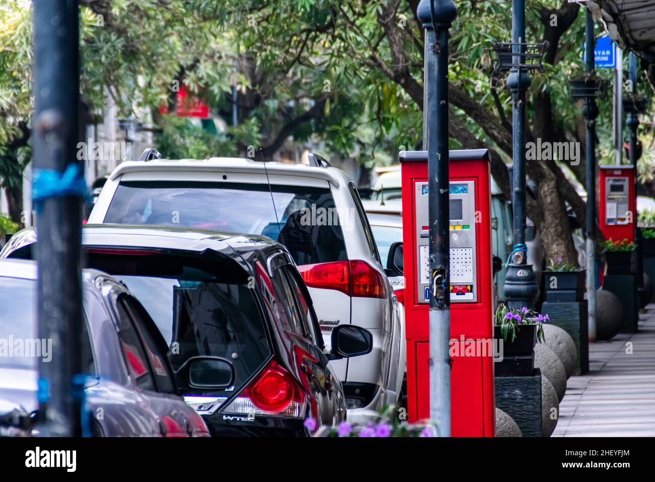 Row of cars on the street park lot at the side of the city street with ...