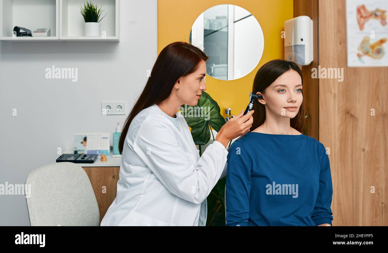 Audiologist woman examining female patient ear with otoscope. Otoscopy ...