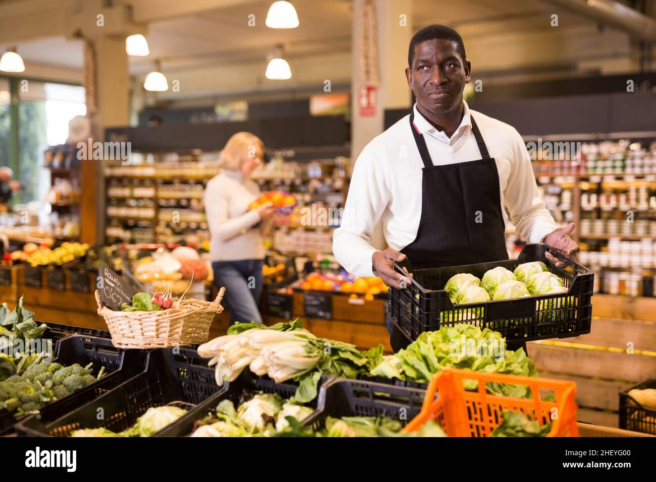 Salesman putting vegetables on store showcase Stock Photo - Alamy