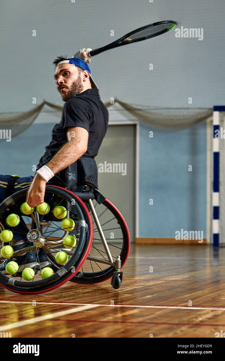 Young man with a physical disability playing tennis on wheelchair on ...
