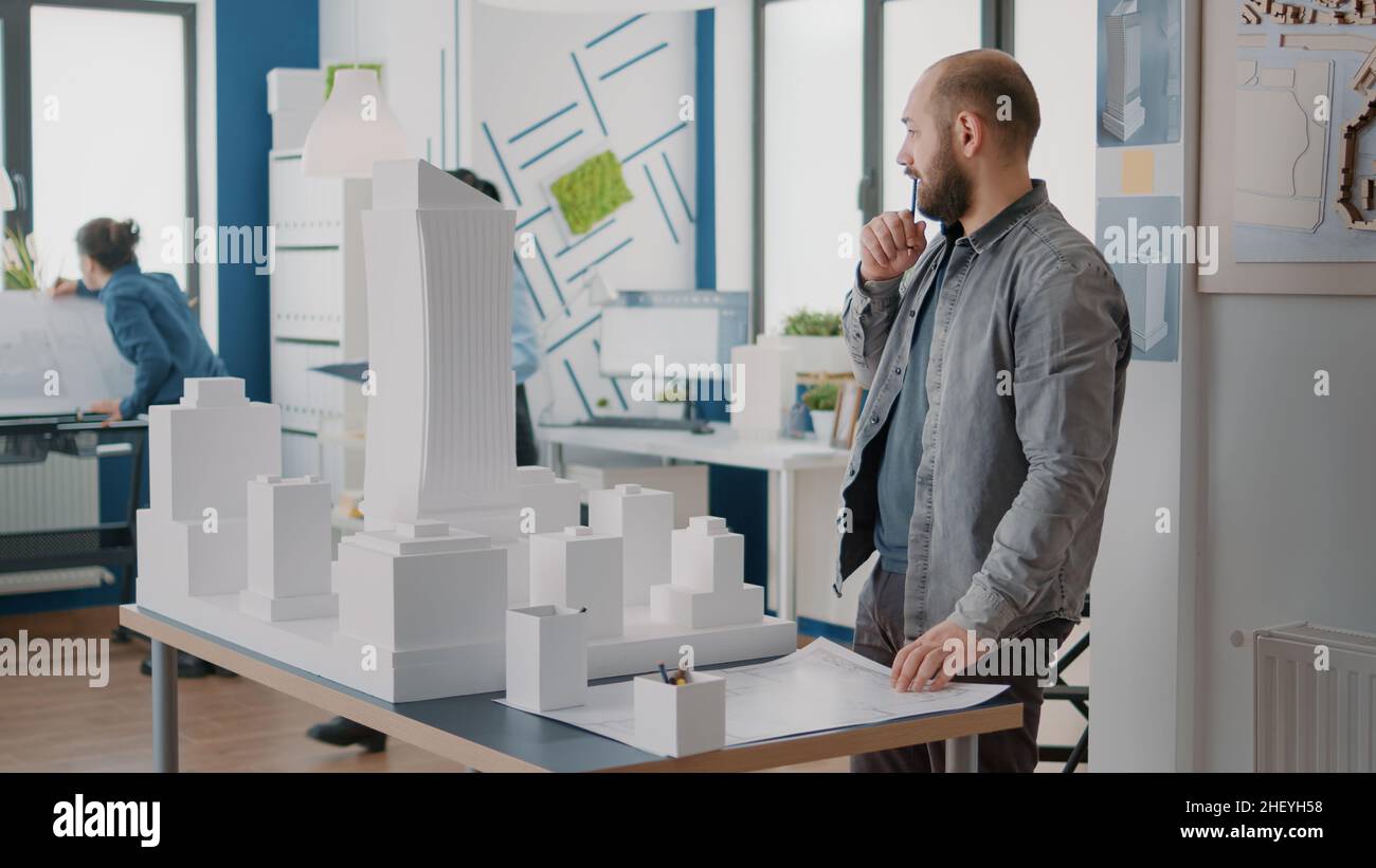 Man Architect Taking Notes On Blueprints Plan To Design Building Structure And Model Industrial