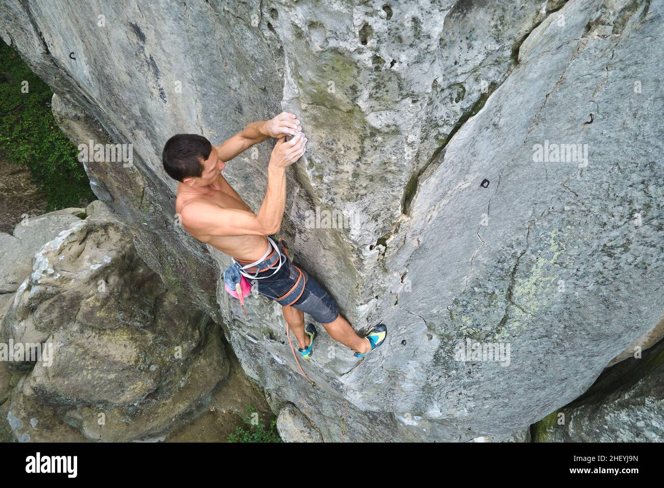 Young man climbing steep wall of rocky mountain. Male climber overcomes ...