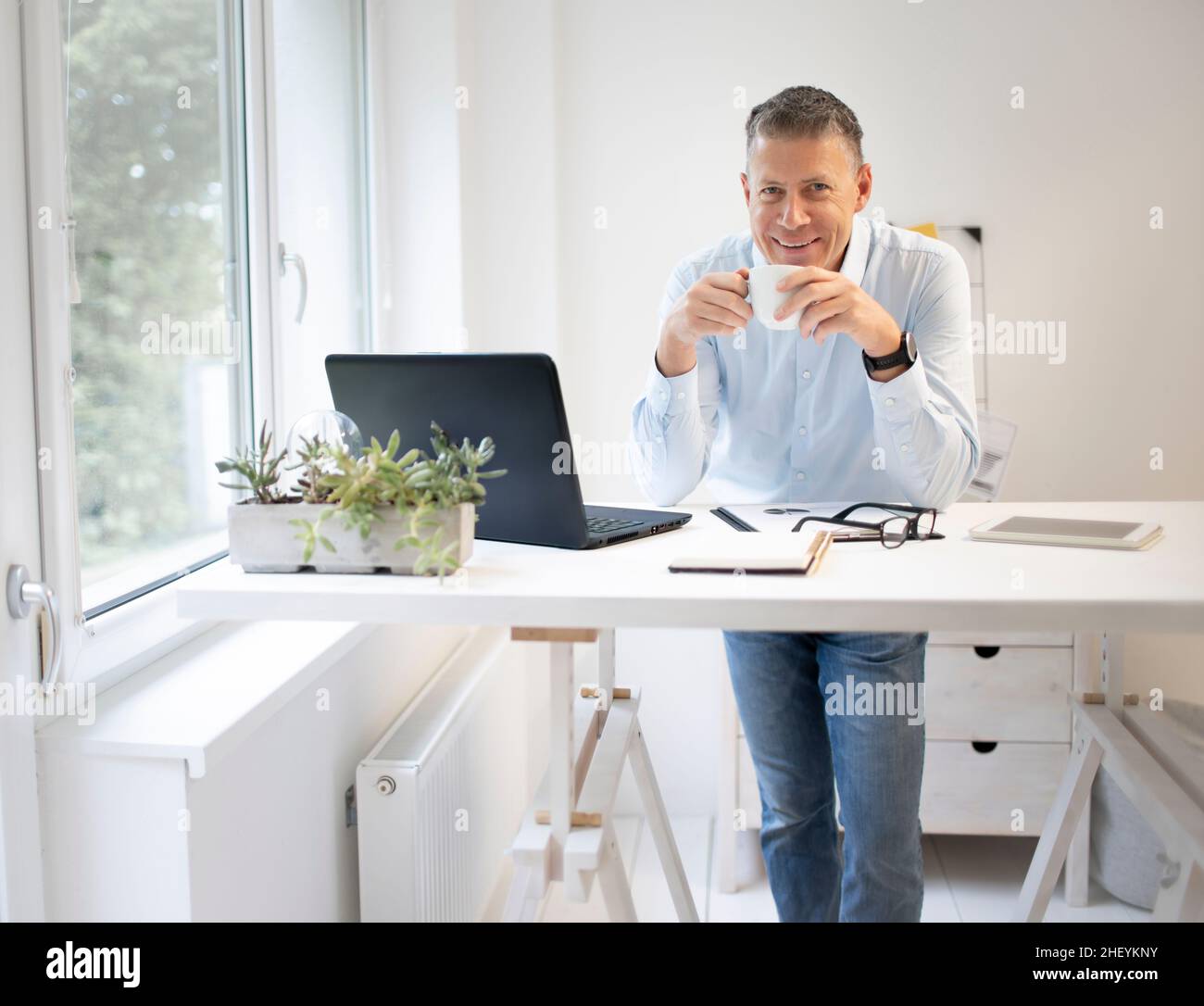 Businessman standing behind bar table with notebook and taking coffee ...