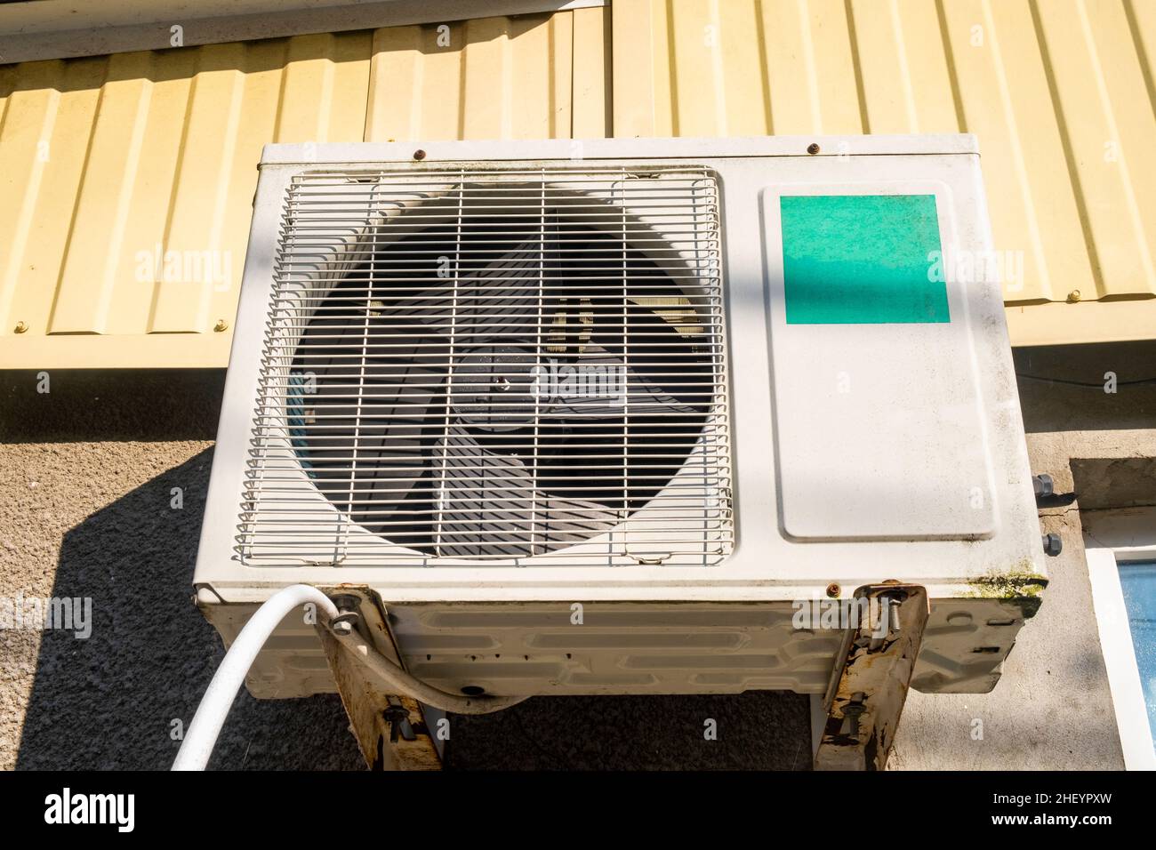 An old and aging air conditioner condenser mounted on the exterior wall ...